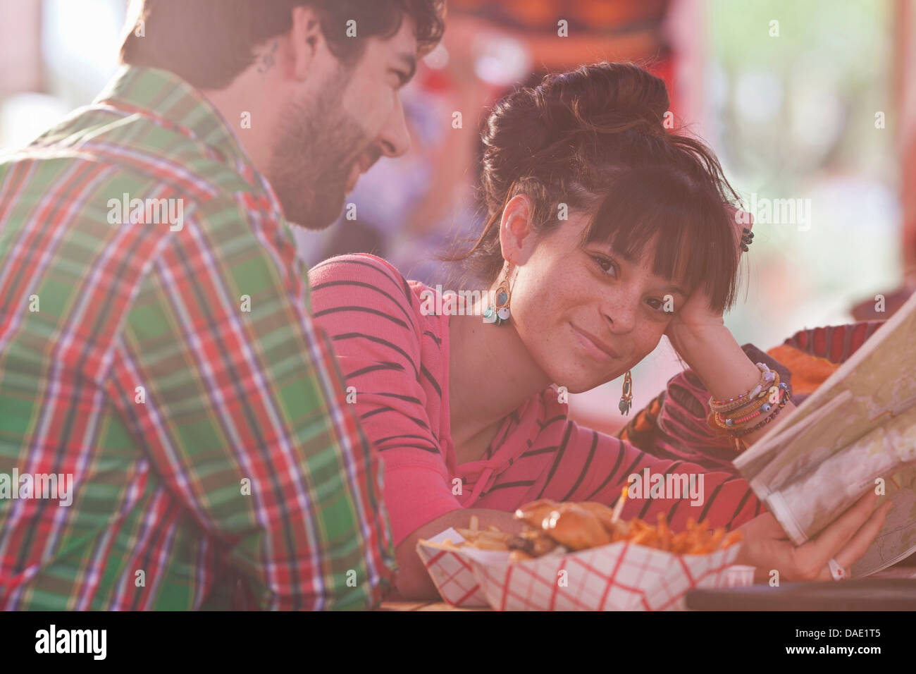 Young woman holding map with man in sunlit diner Stock Photo - Alamy