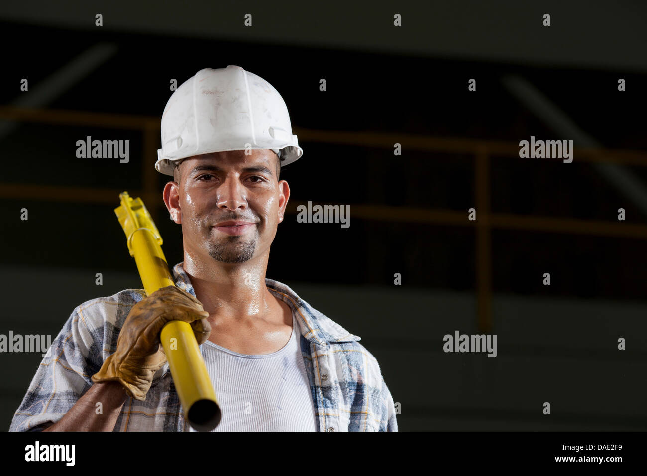 Mid adult construction worker wearing hard hat and holding tool ...