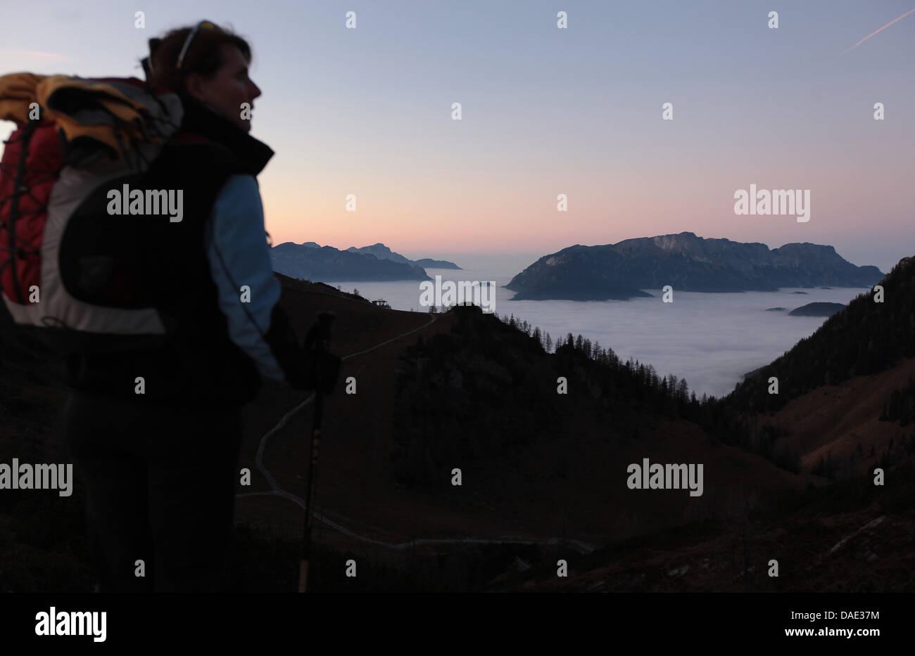 A mountain hiker wanders across a range passing a valley covered in fog ...