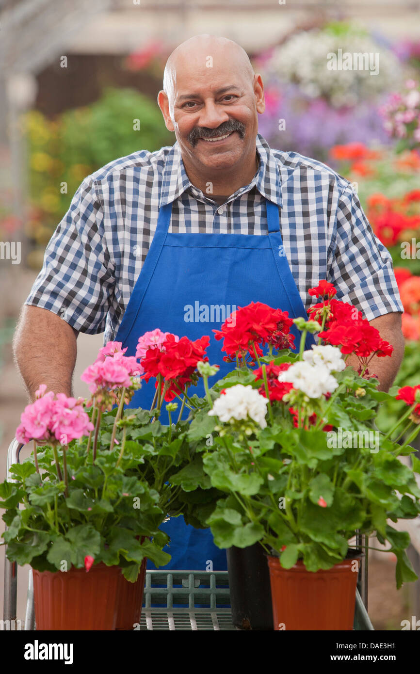 Mature gardener working in garden centre, smiling Stock Photo - Alamy