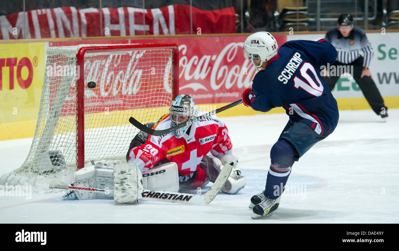 Swiss hockey goalkeeper Reto Berra (L) parades the puck of attacking US ...