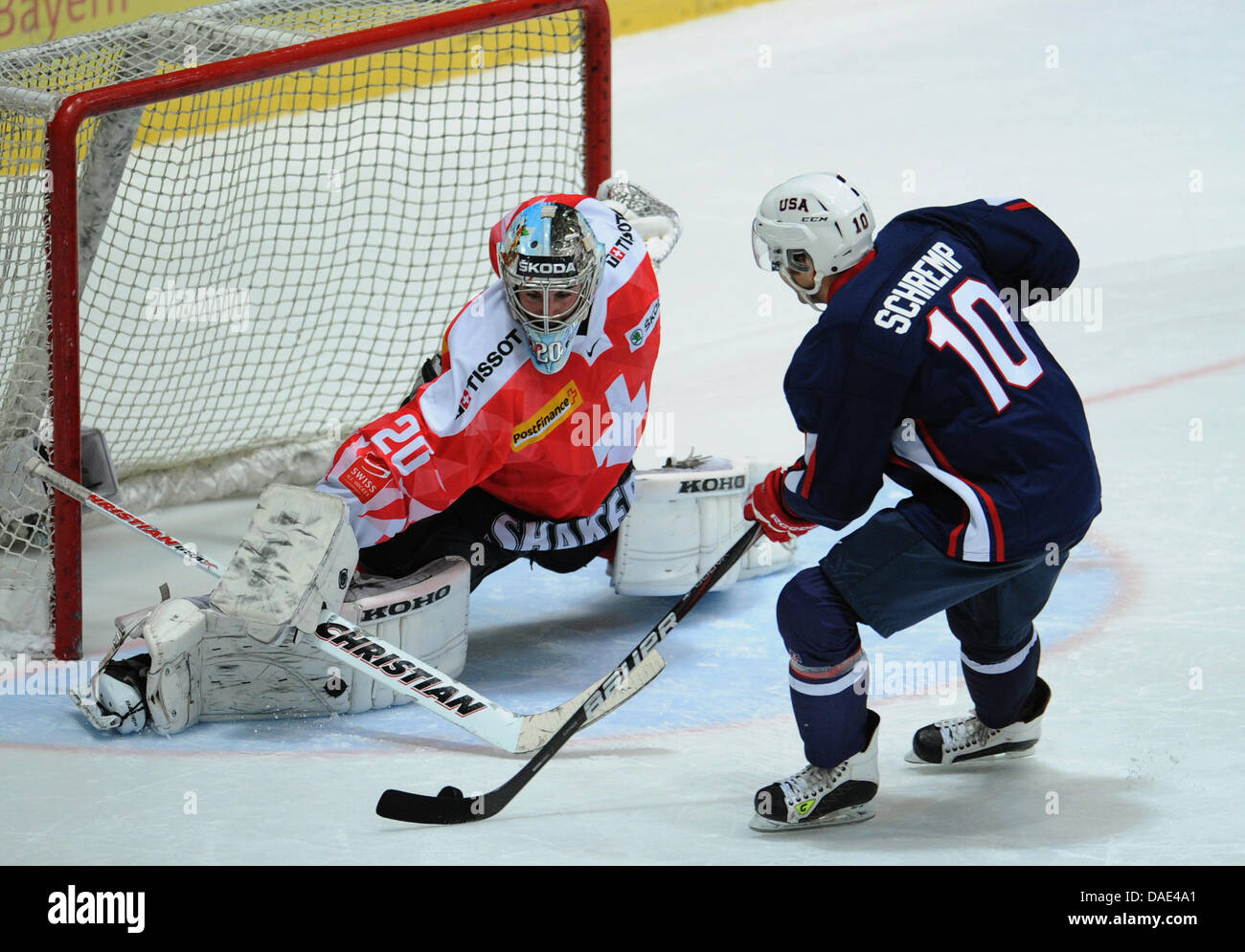 Swiss hockey goalkeeper Reto Berra (L) parades the puck of attacking US ...