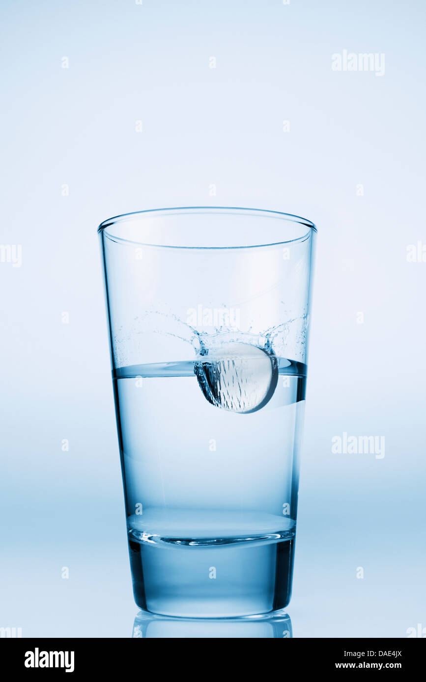Tablet falling in glass of water Stock Photo - Alamy