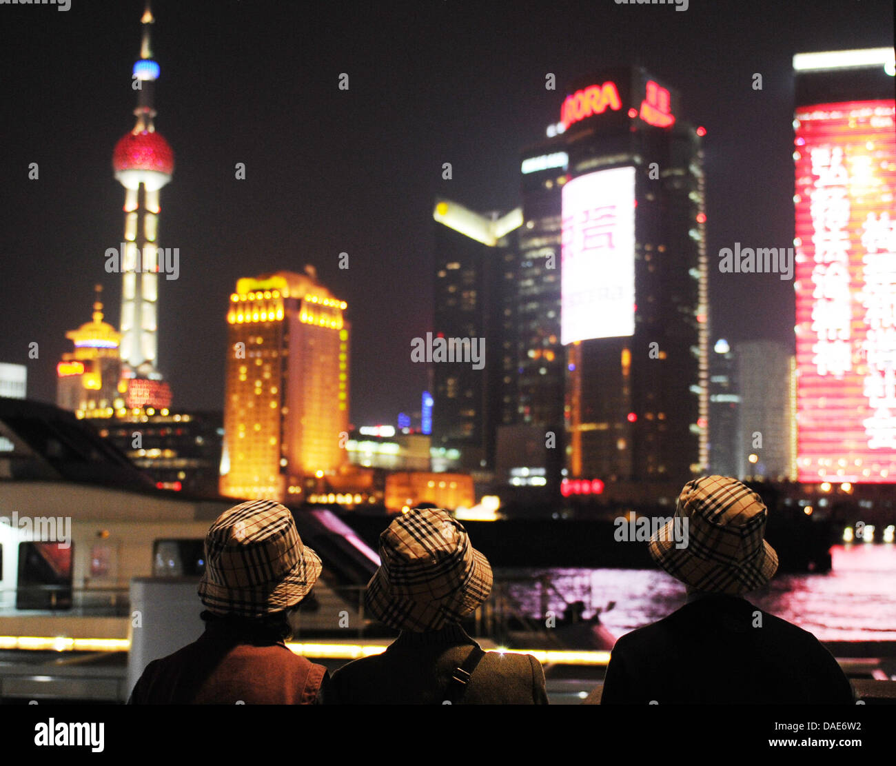 Three women wearing the same hat look at the skyline of Shanghai, China ...