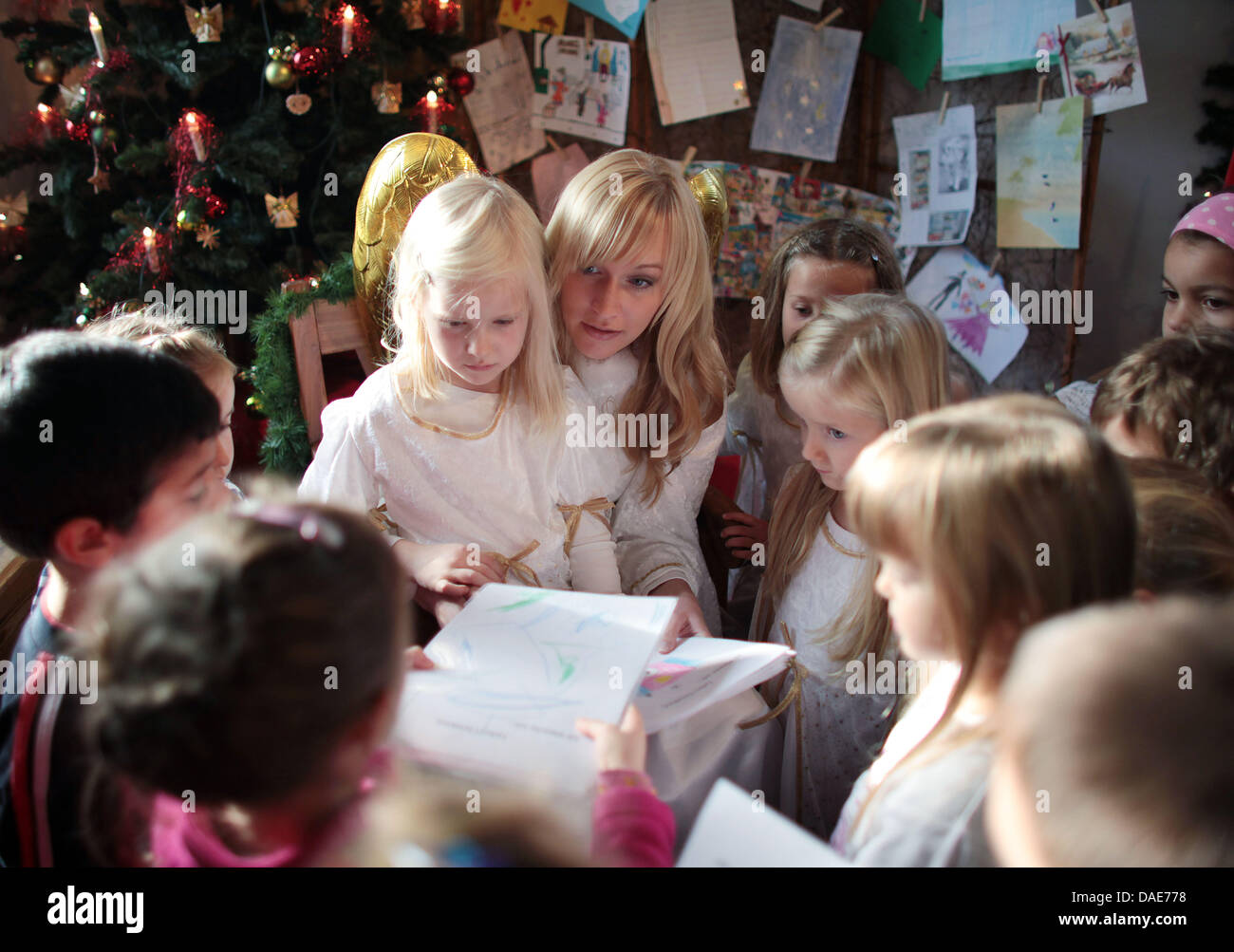 A Christ Child impersonator (R) with an 'angel' on her lap accepts ...