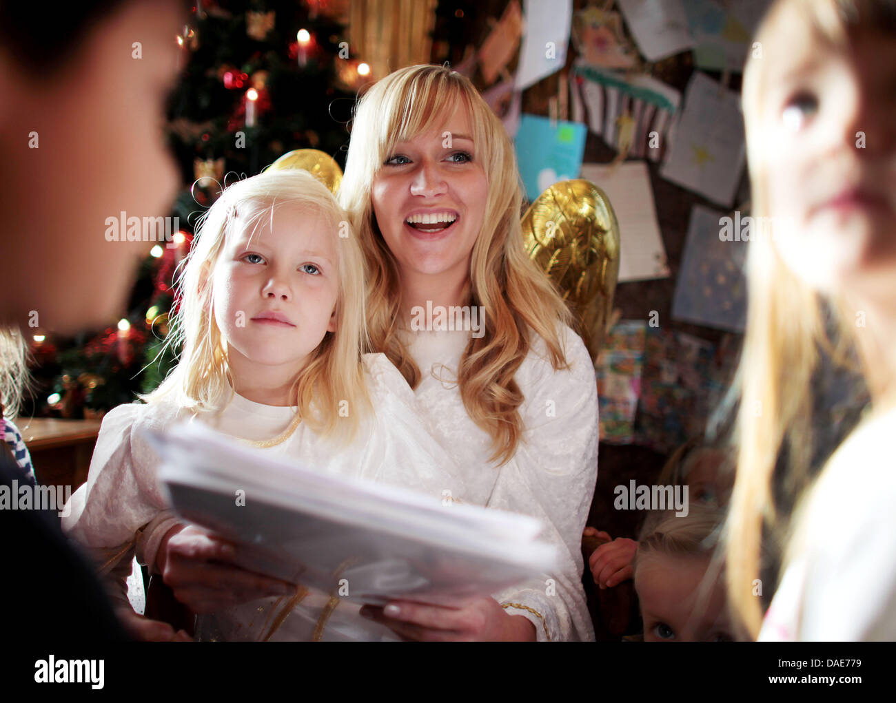 A Christ Child impersonator (R) with an 'angel' on her lap accepts ...