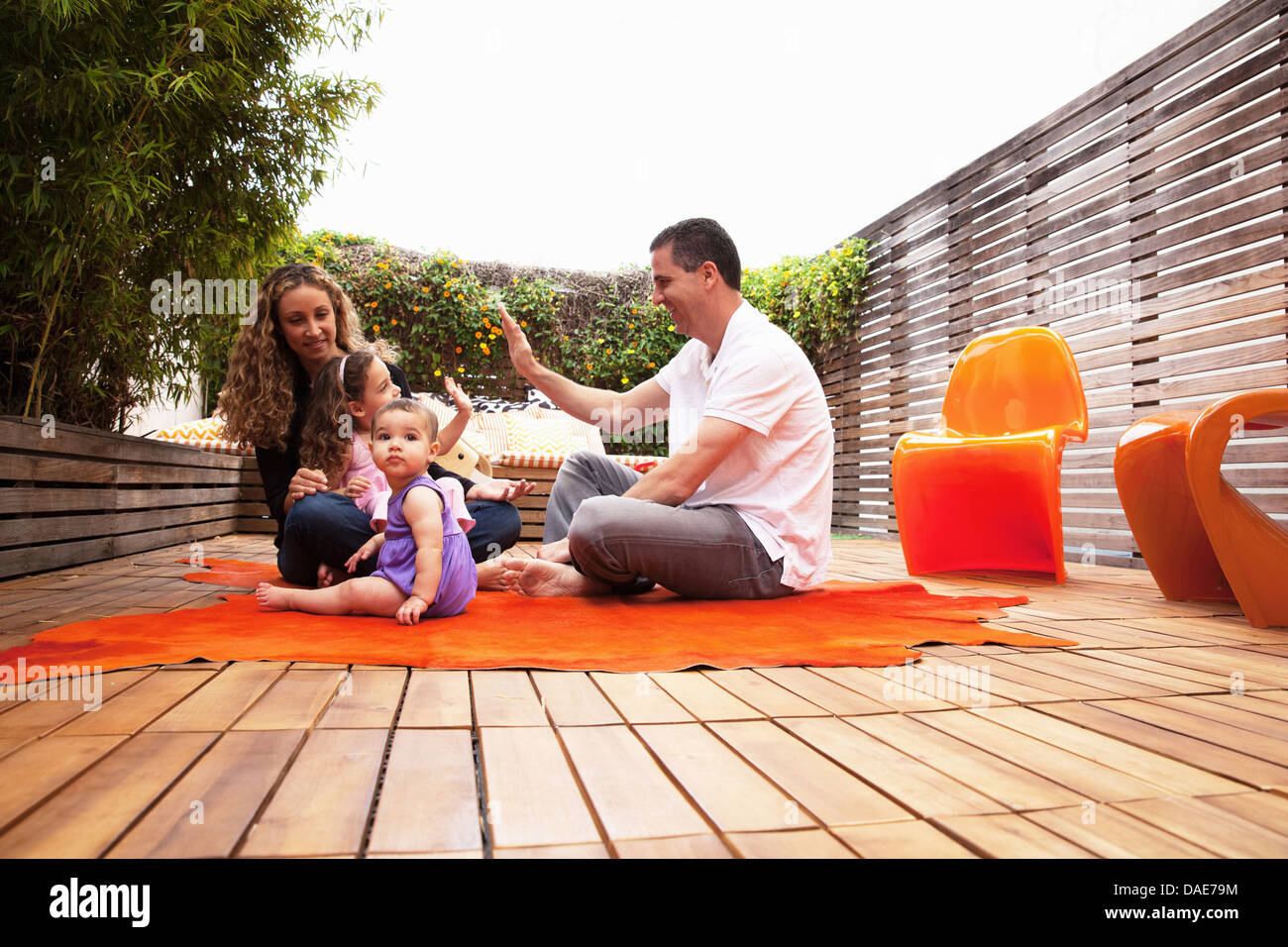 Family sitting on rug on patio Stock Photo - Alamy