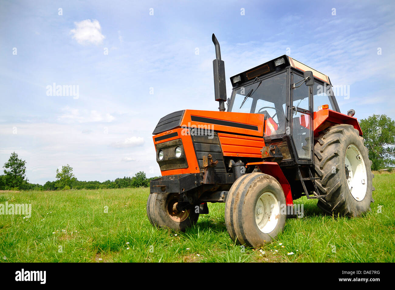 Red tractor on the meadow Stock Photo - Alamy