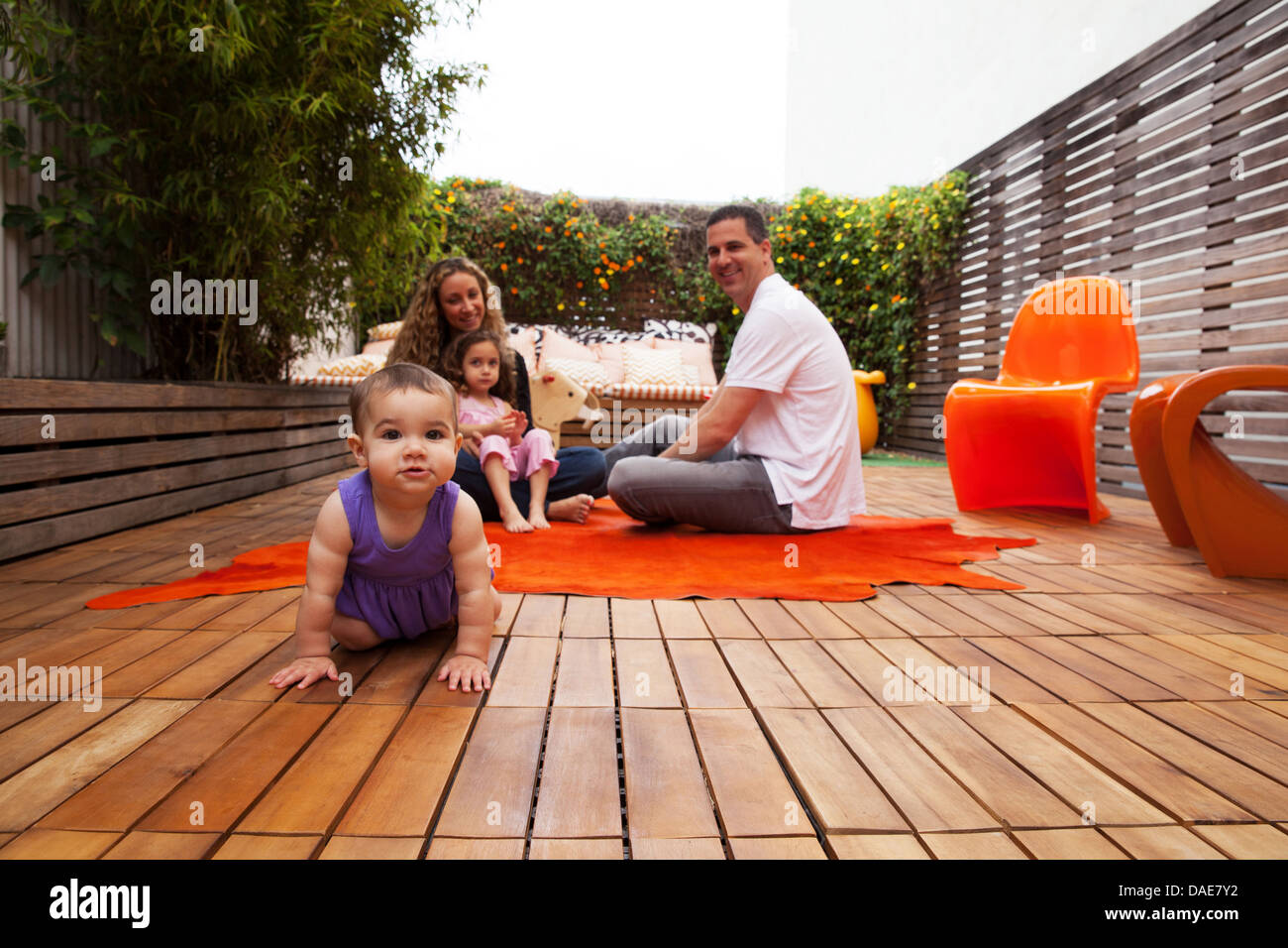 Family sitting on patio with baby girl crawling in foreground Stock ...