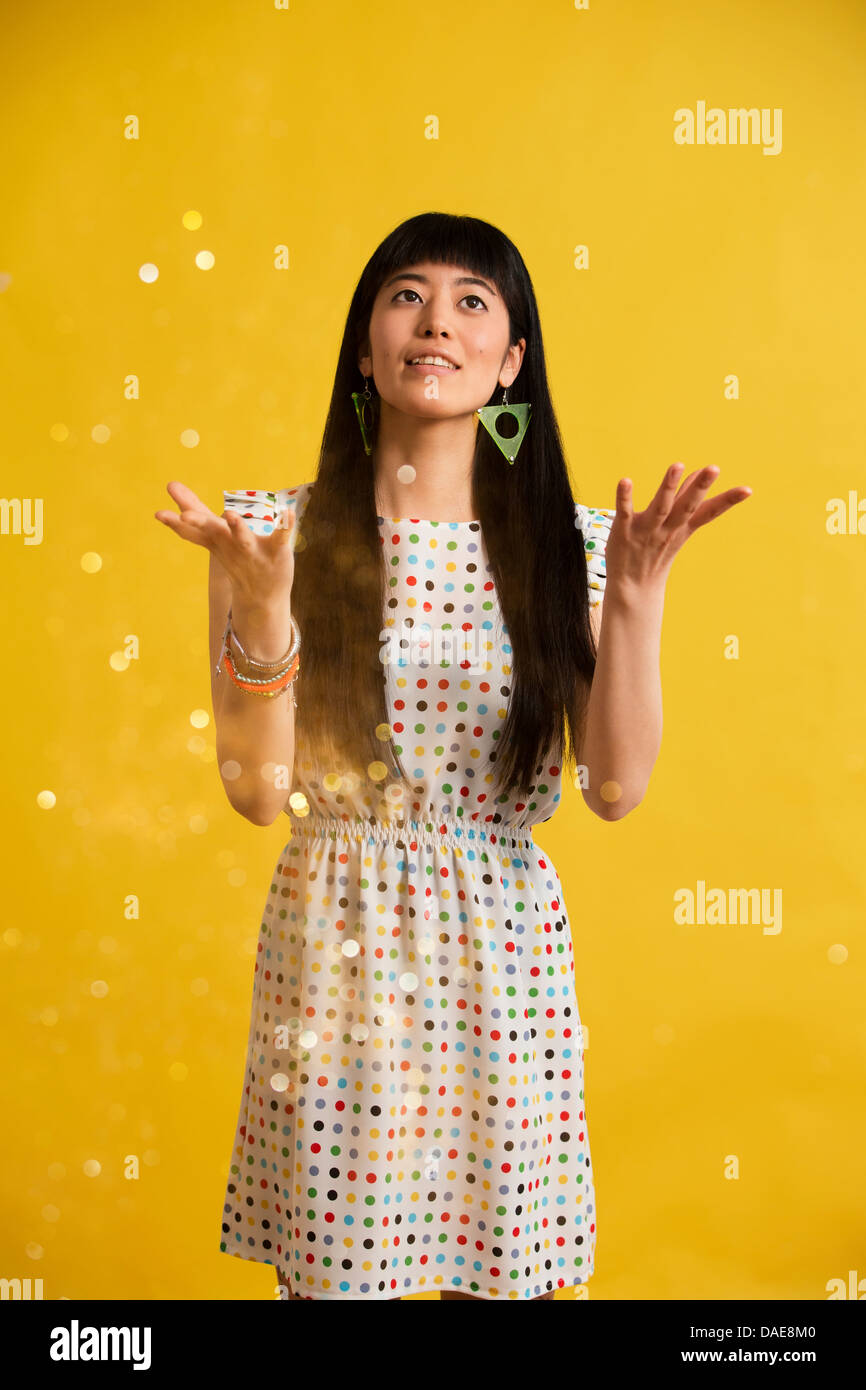 Portrait of young woman wearing spotted dress catching glitter Stock ...