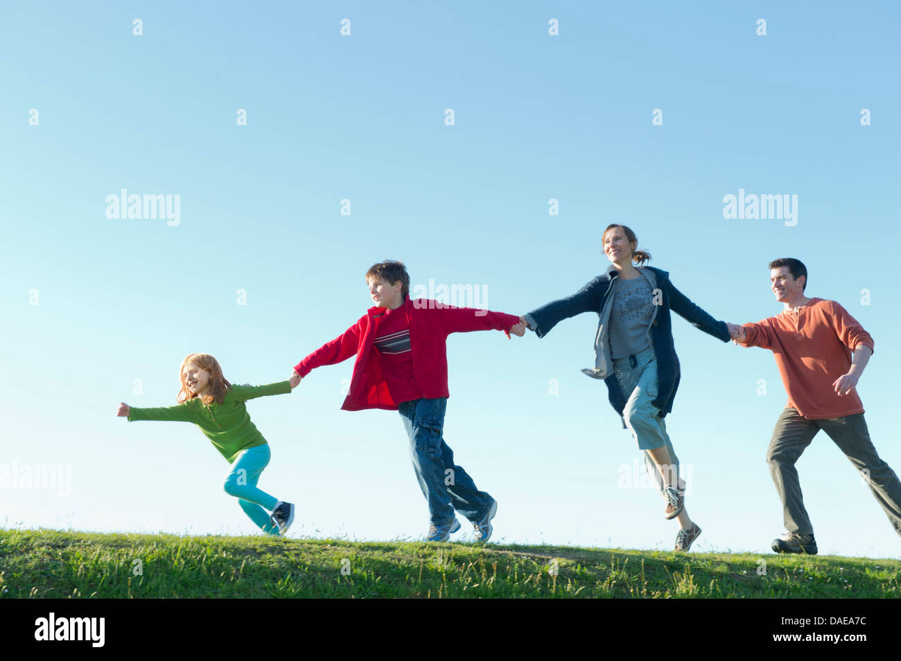 Parents and two children running and holding hands Stock Photo - Alamy