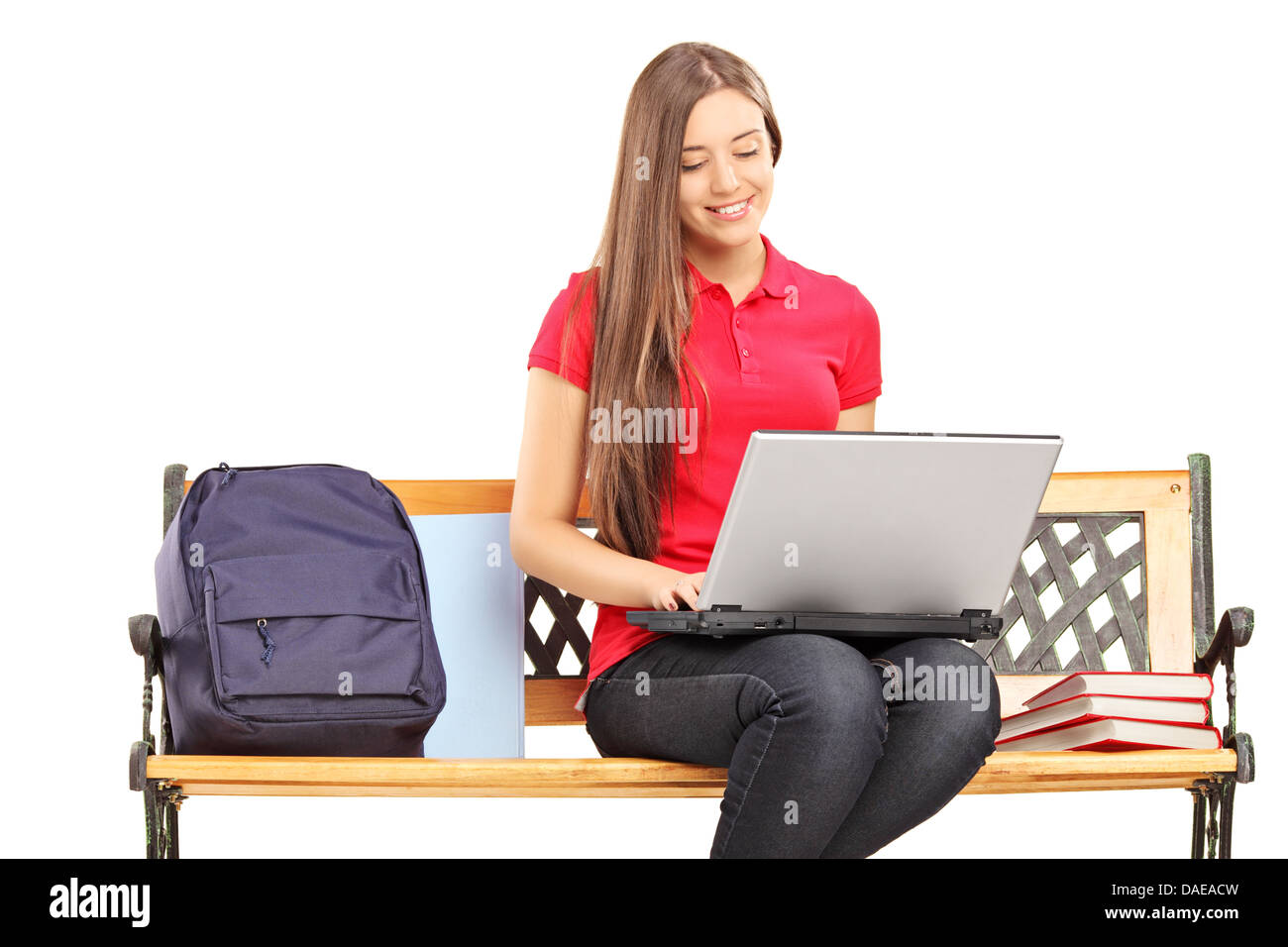 Smiling female student sitting on a wooden bench and working on a ...