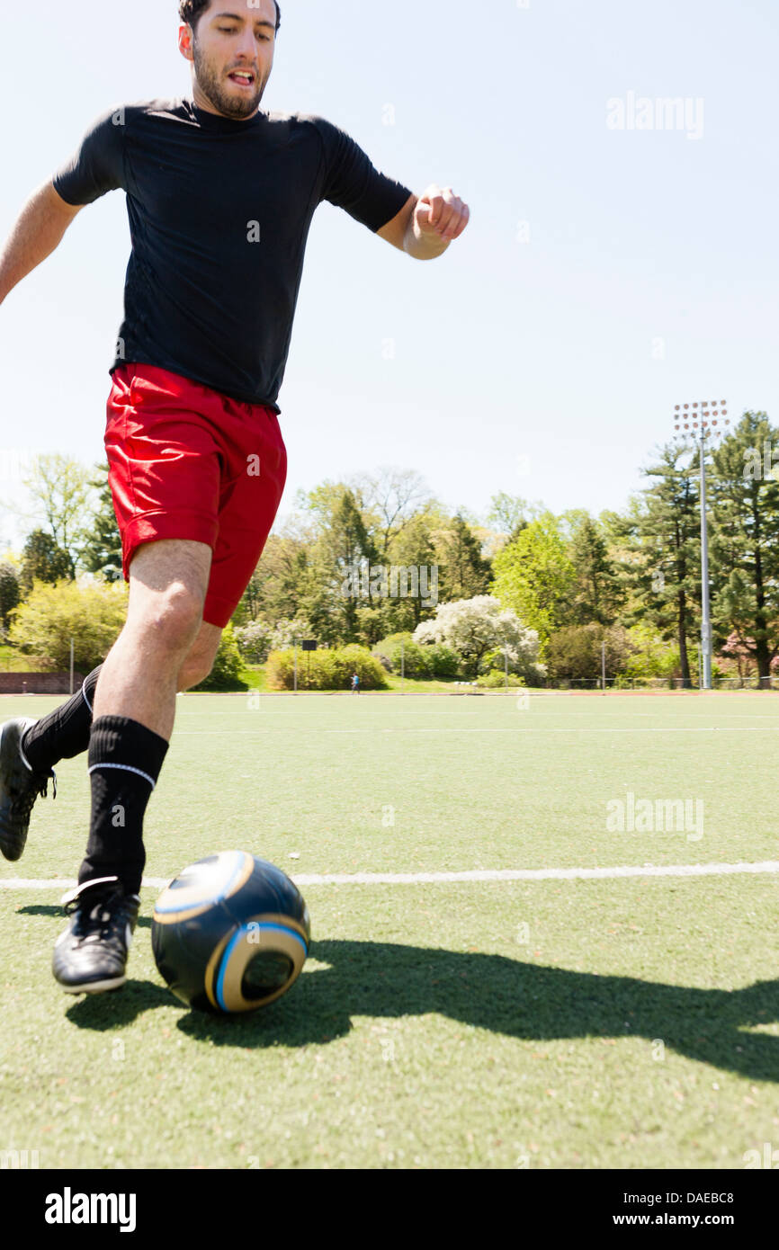Soccer player running and dribbling ball Stock Photo - Alamy