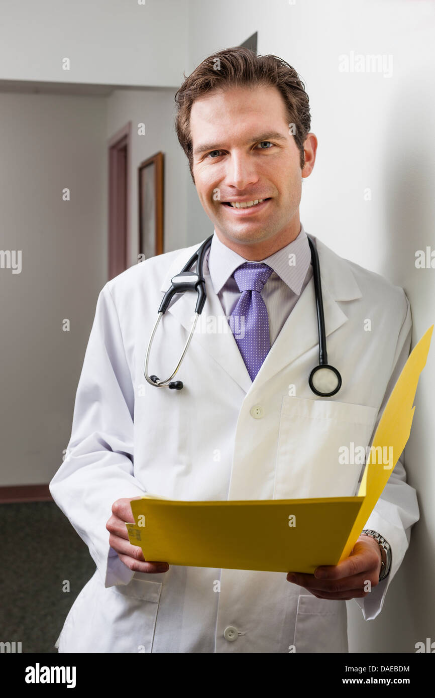 Doctor holding file in hospital corridor, portrait Stock Photo - Alamy