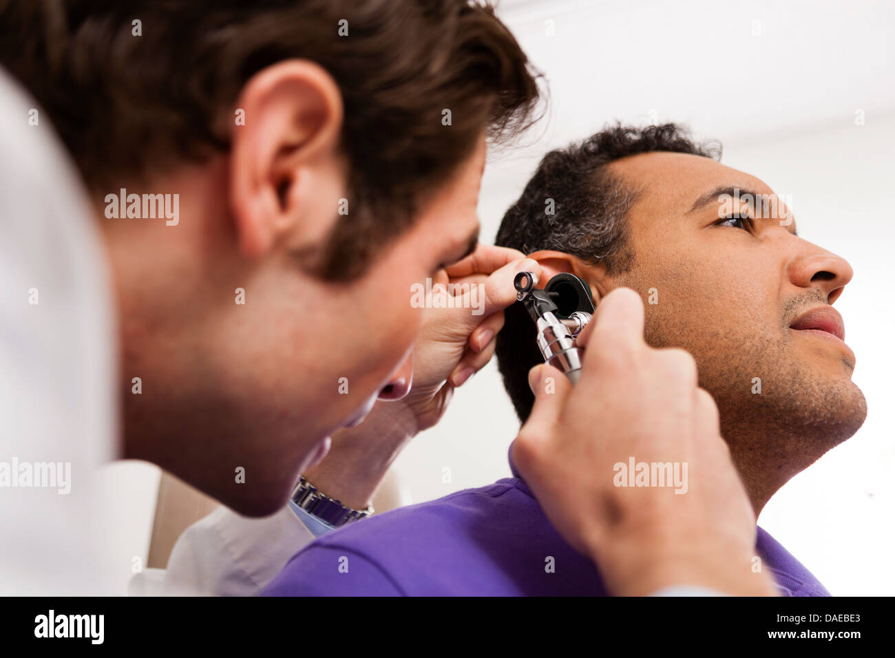 Mid adult doctor using otoscope on patient Stock Photo - Alamy