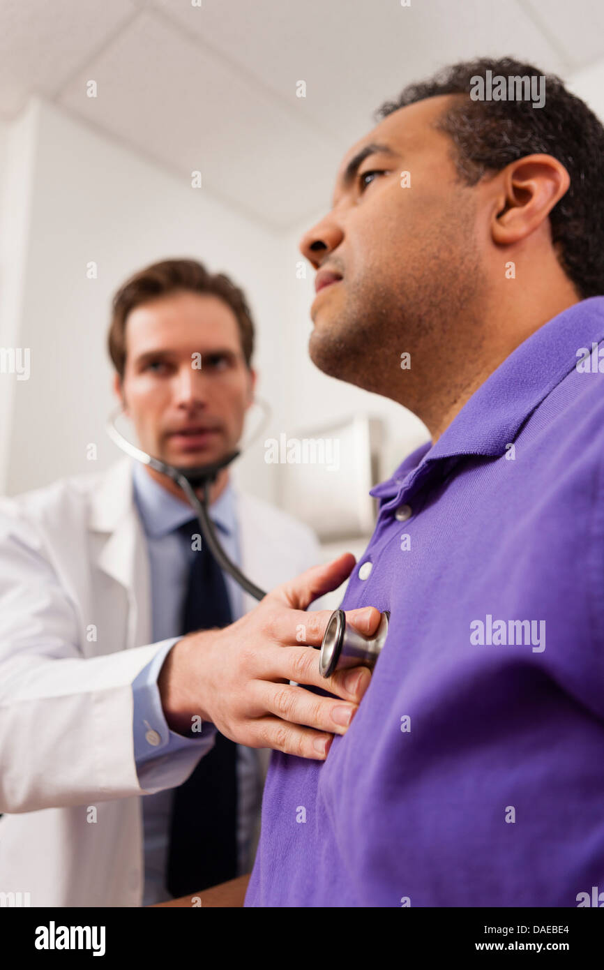 Mid adult doctor using stethoscope on patient Stock Photo - Alamy