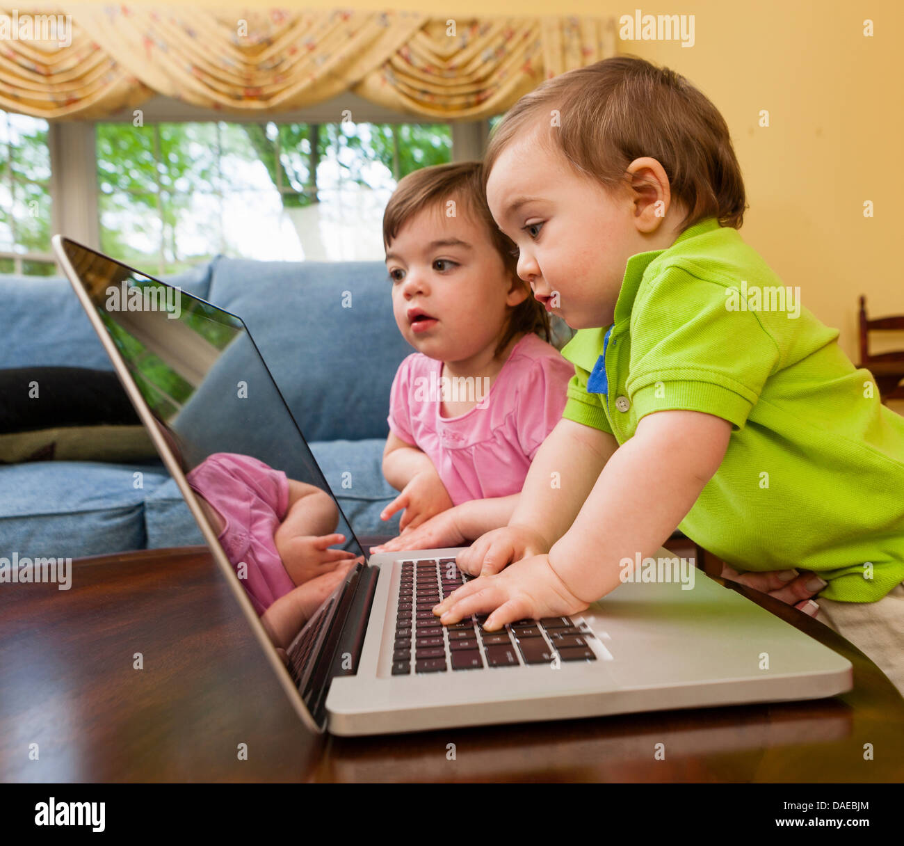 Two young toddlers playing with laptop Stock Photo - Alamy