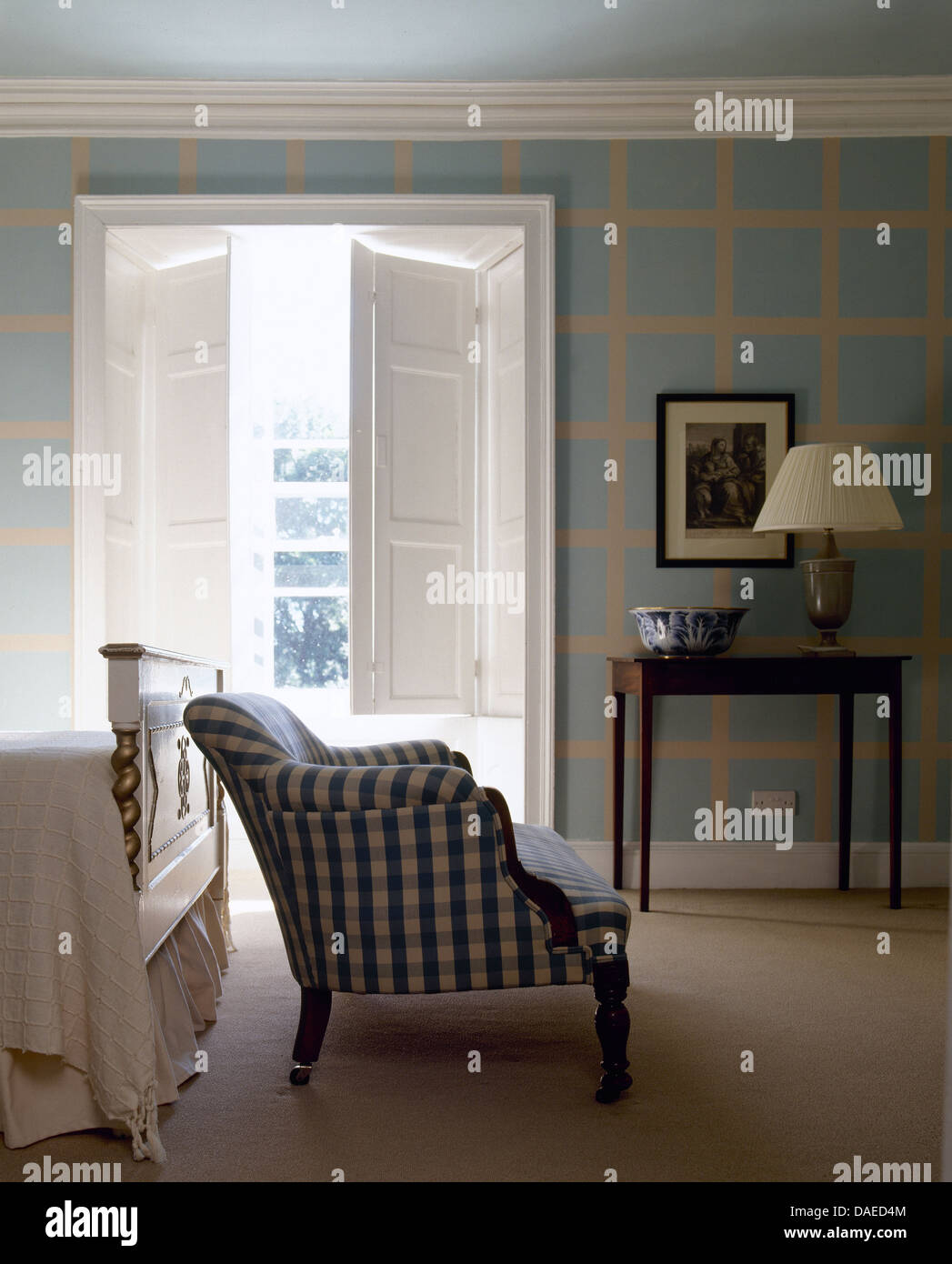 Blue checked armchair at the foot of the bed in tranquil bedroom with ...