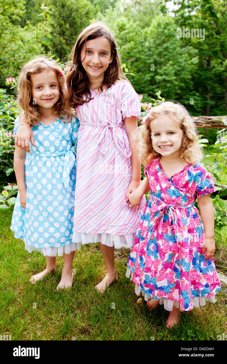Three Smiling Sisters in Colorful Dresses Holding Hands Stock Photo - Alamy