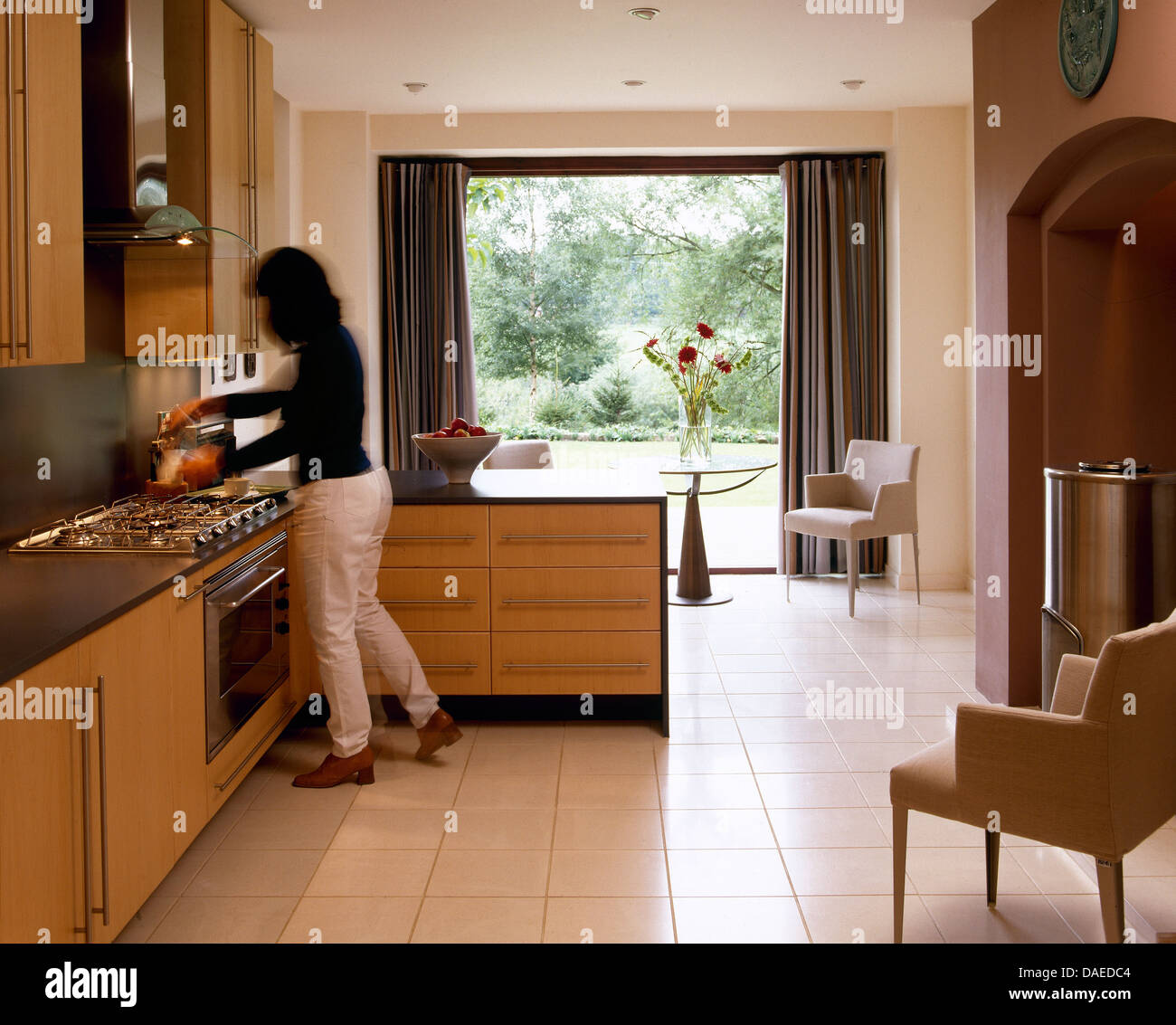 Woman standing at oven in modern kitchen Stock Photo - Alamy