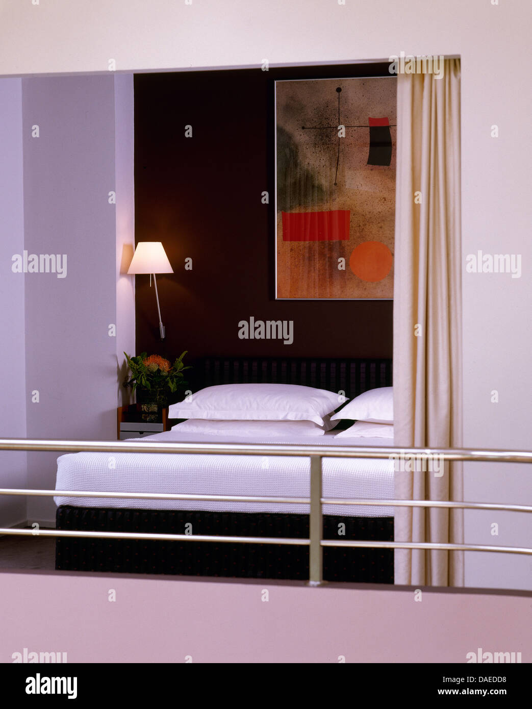 Chrome banisters on landing with view of lamp beside bed with white ...