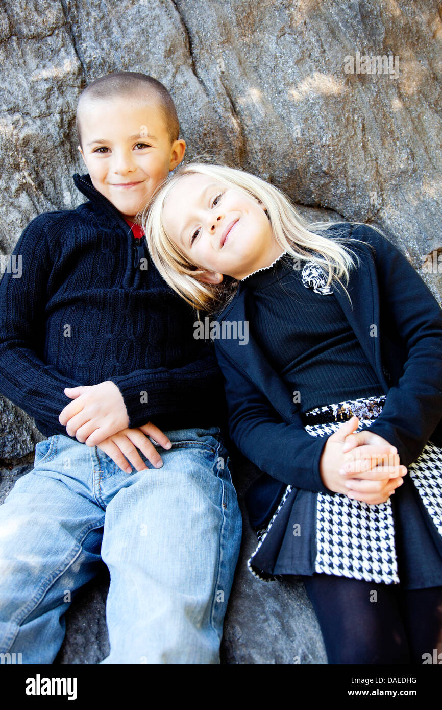 Smiling Boy and Girl Leaning Against Rock Stock Photo - Alamy