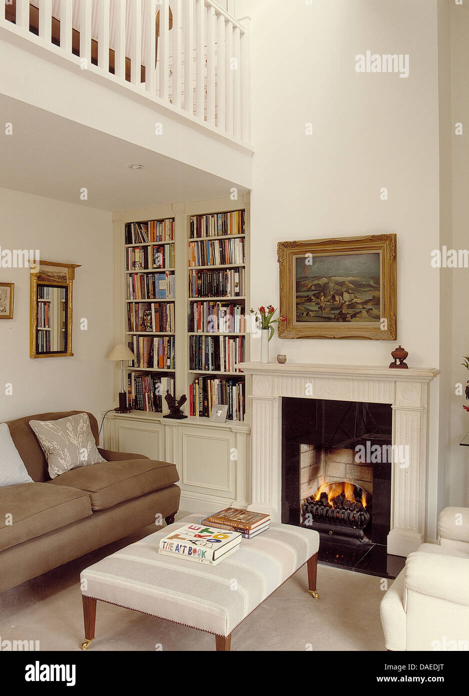 Beige sofa and upholstered stool in front of fireplace in white split ...