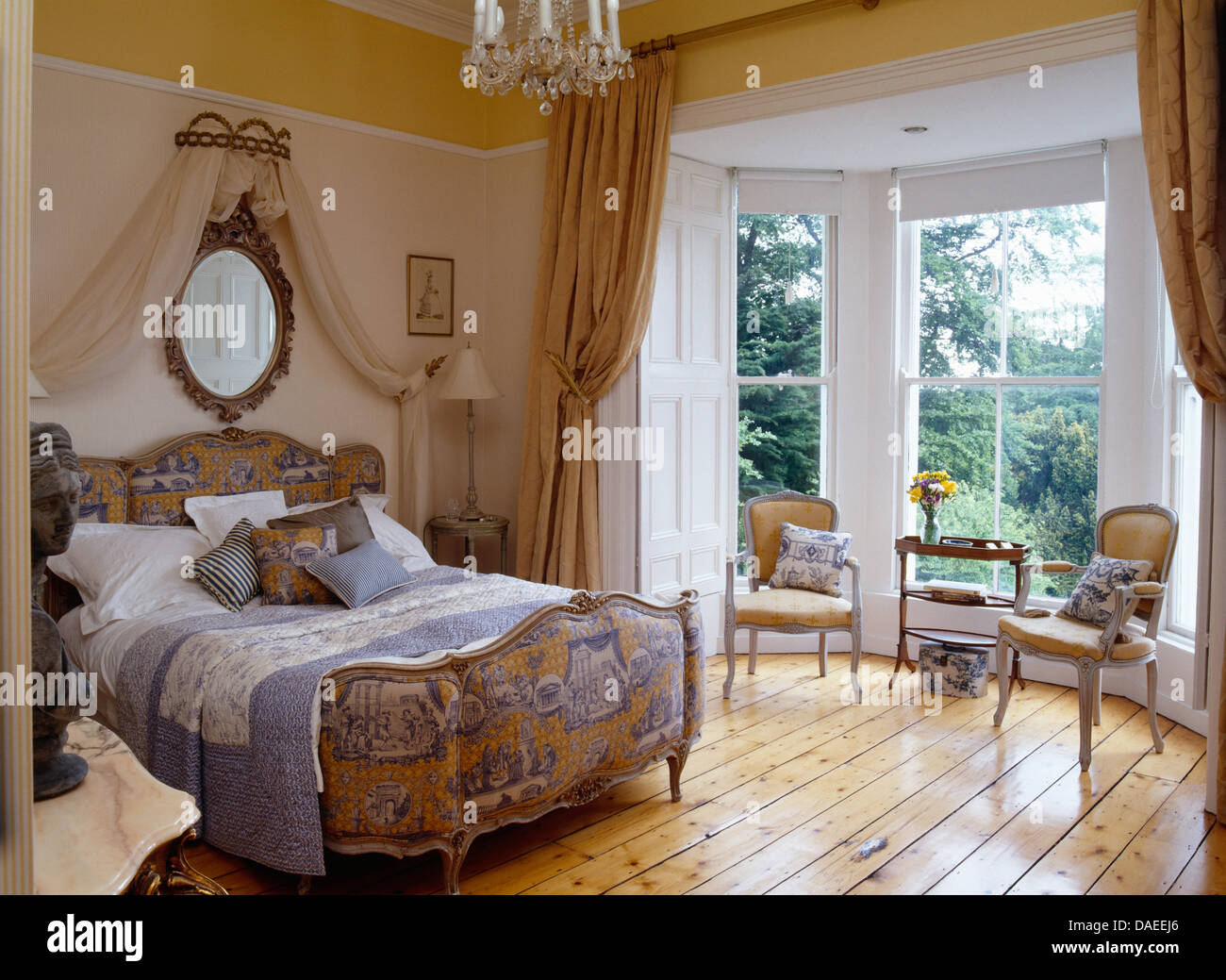 Mirror and coronet with voile drapes above upholstered French bed in ...