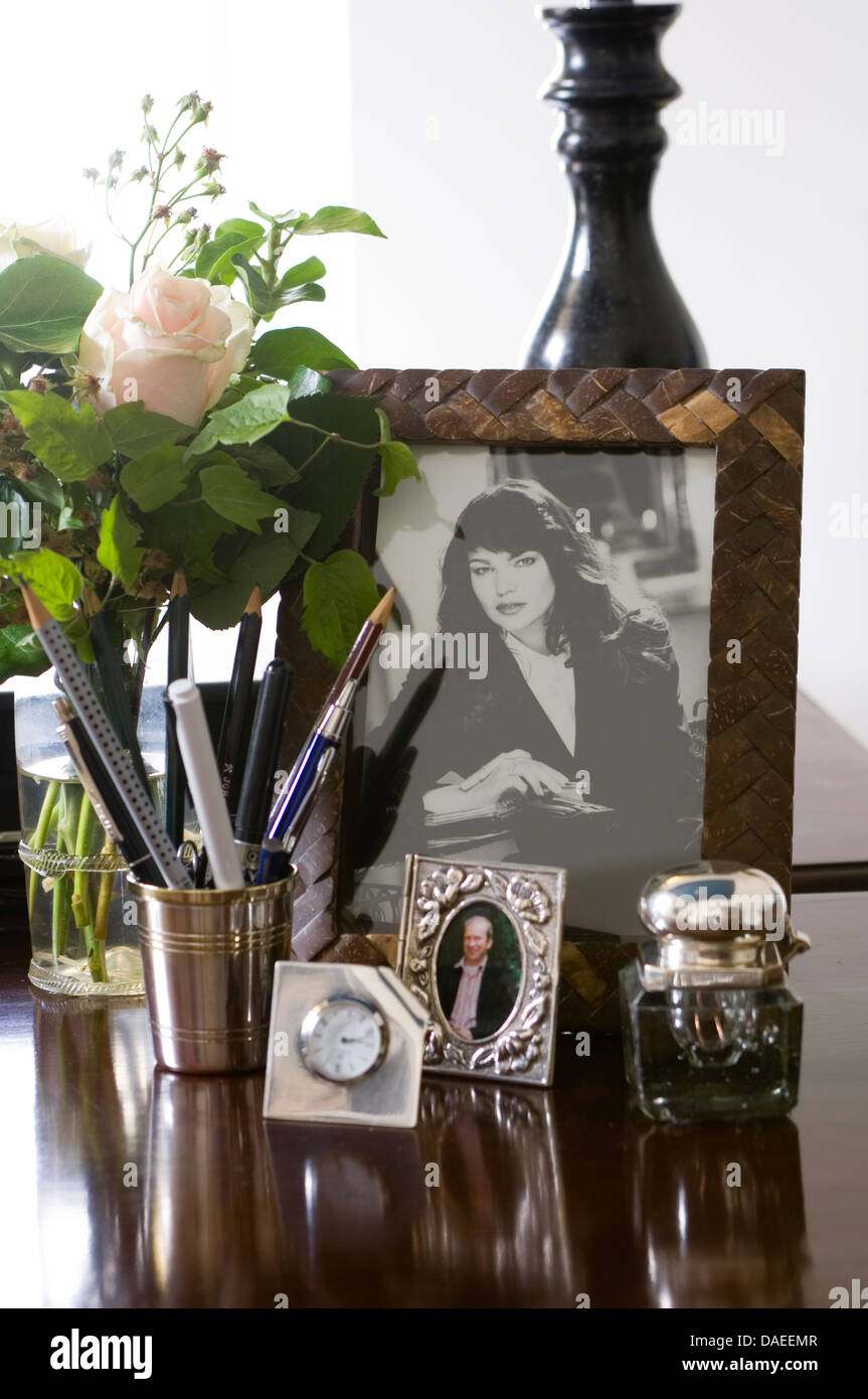 Still-Life of framed photograph and silverware on table with pink rose ...