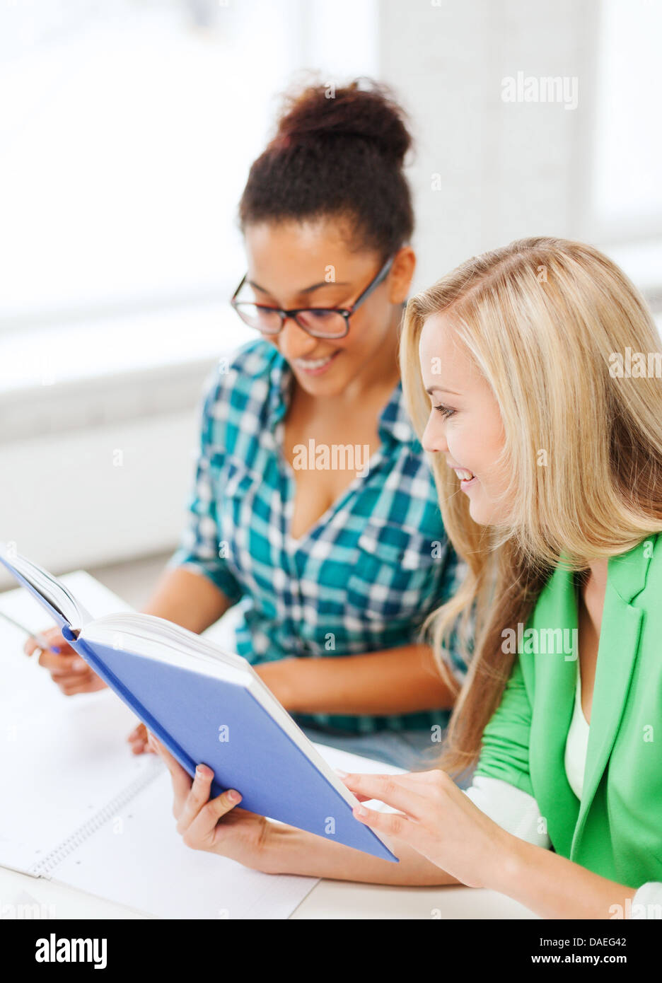 smiling student girls reading book at school Stock Photo - Alamy