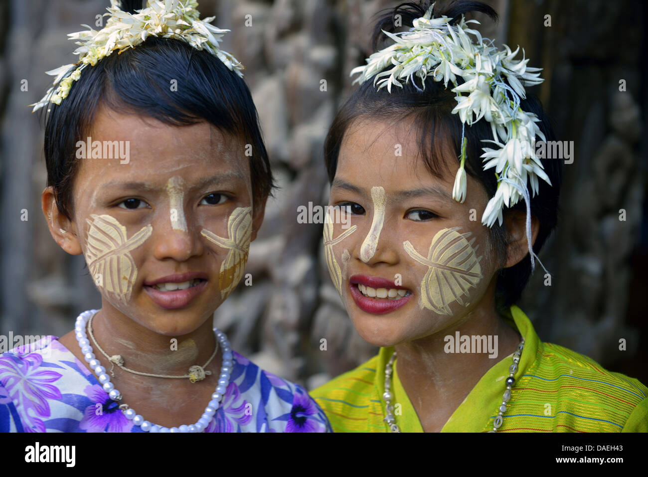 two young flower sellers made up with the traditional Burmese thanaka ...