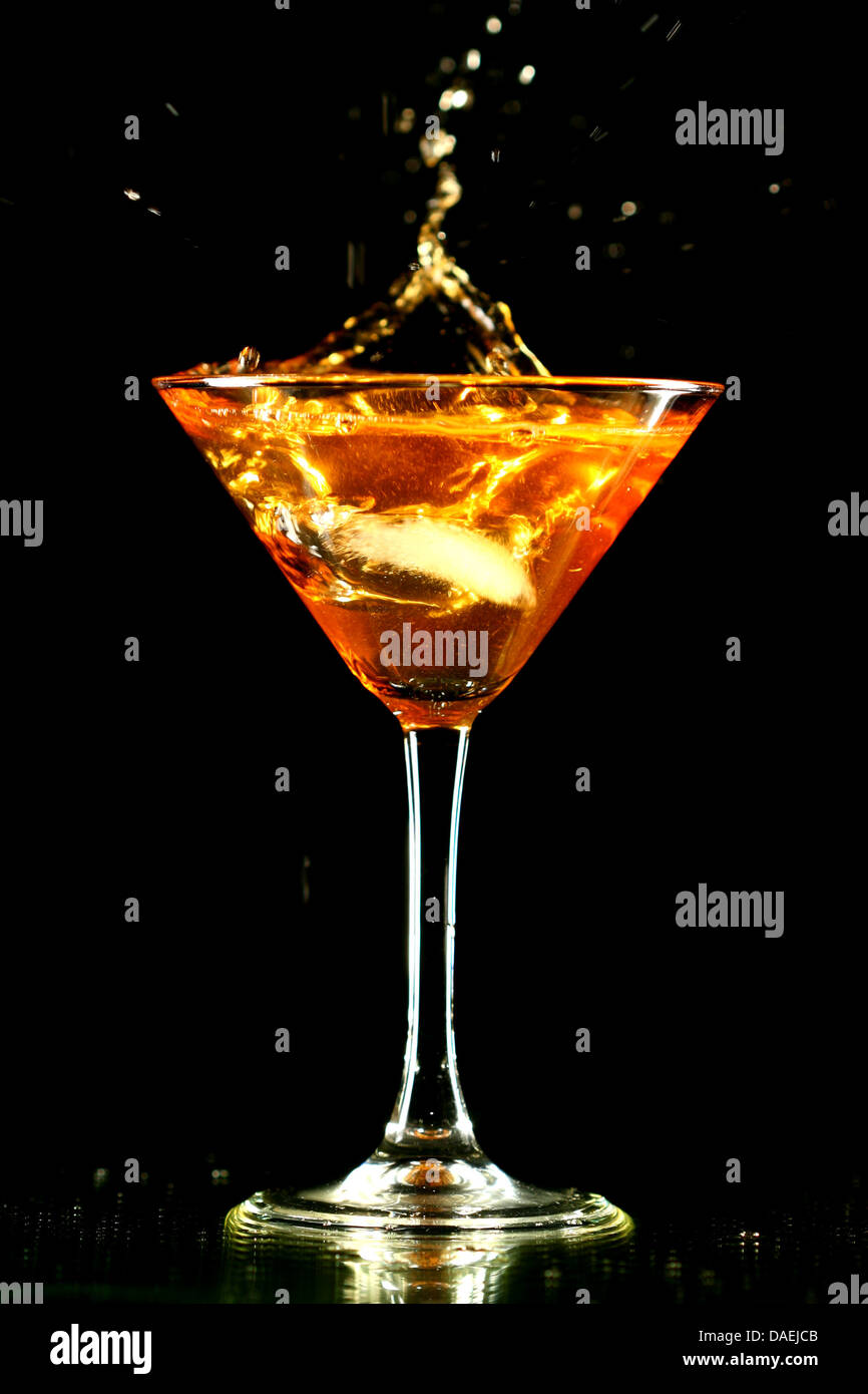 alcohol splash in martini glass on black background Stock Photo - Alamy