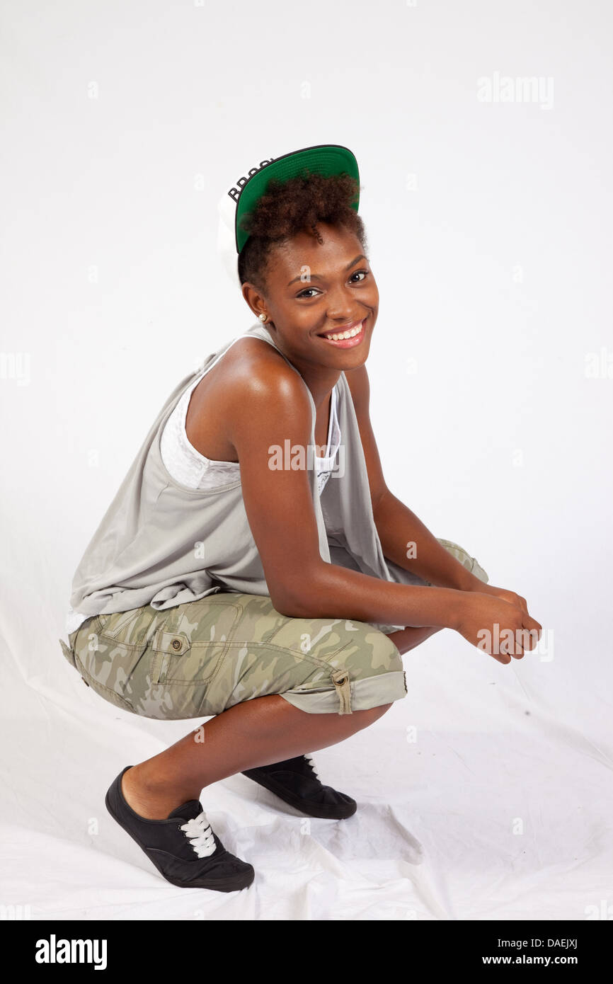Cute black woman squatting on the floor and looking at the camera with ...