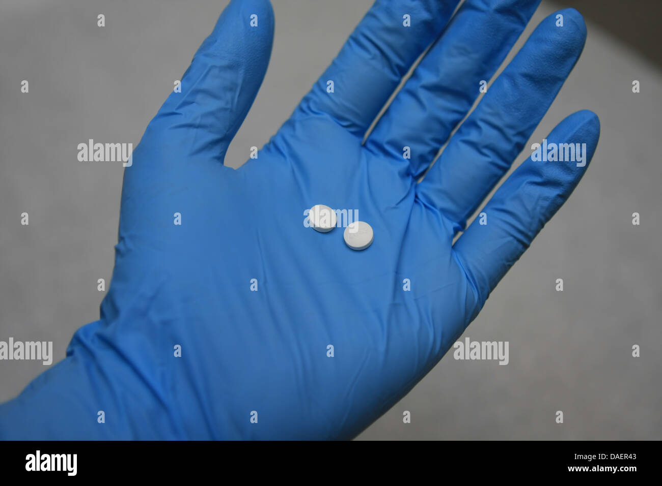 two pills in blue gloved hand Stock Photo - Alamy