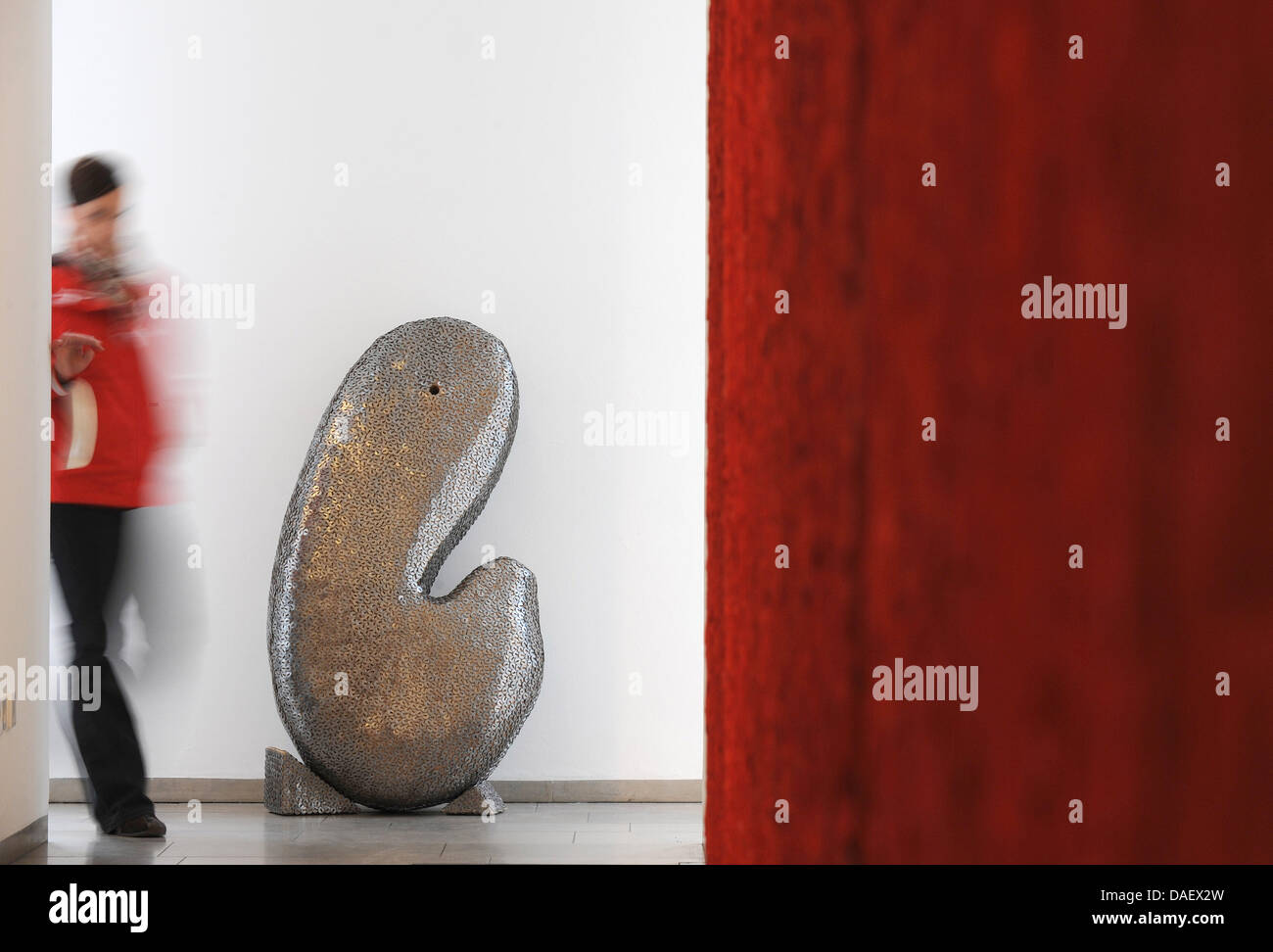 An employee walks past a silver shimmering hook sculpture from the ...