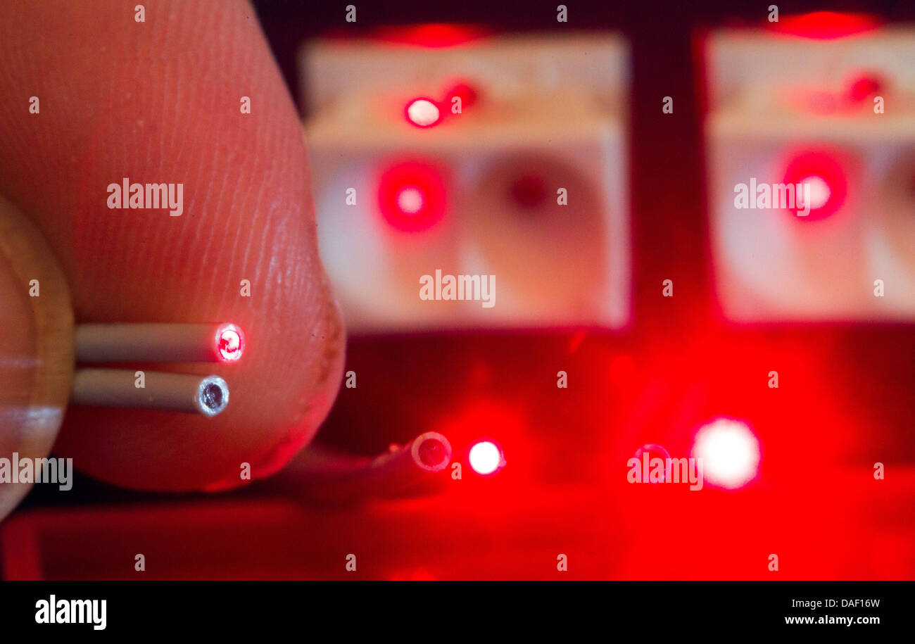 A red glowing fiber optic cable for household fiber optic networks are ...