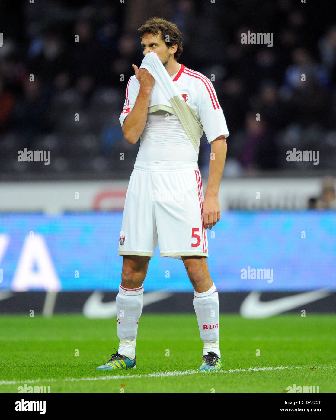 Leverkusen's Manuel Friedrich stands disappointed on the pitch, wiping ...