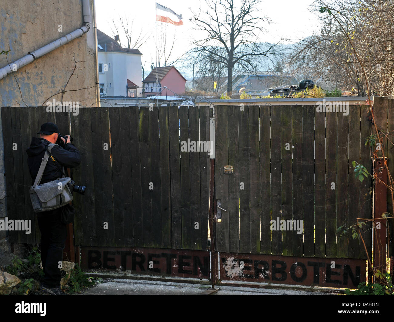 A photographer photographs a German imperial flag through a gate of the ...