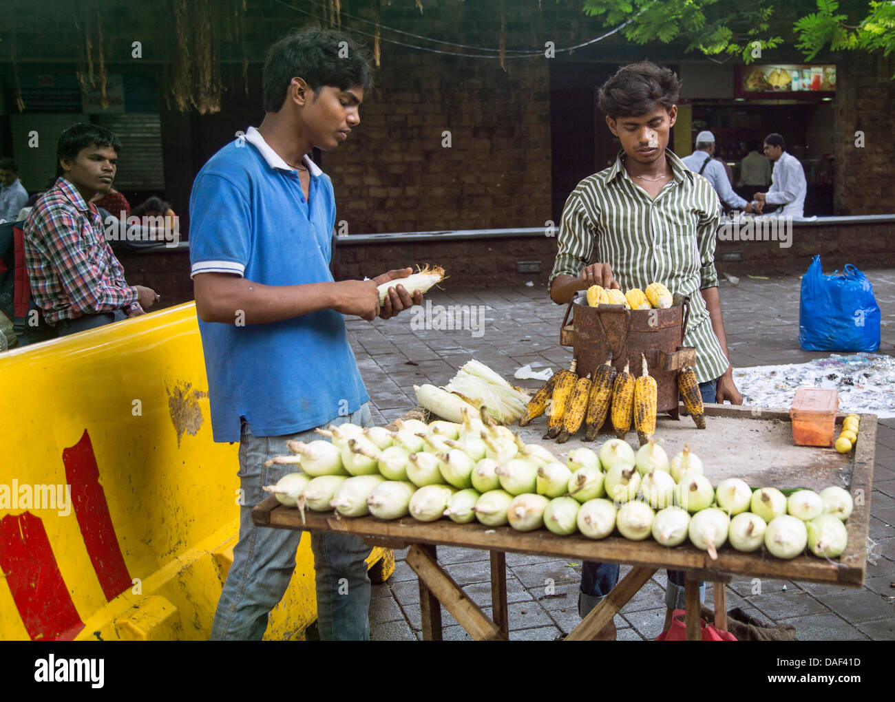 Two men selling roasted sweet corn on cob roadside Stock Photo - Alamy