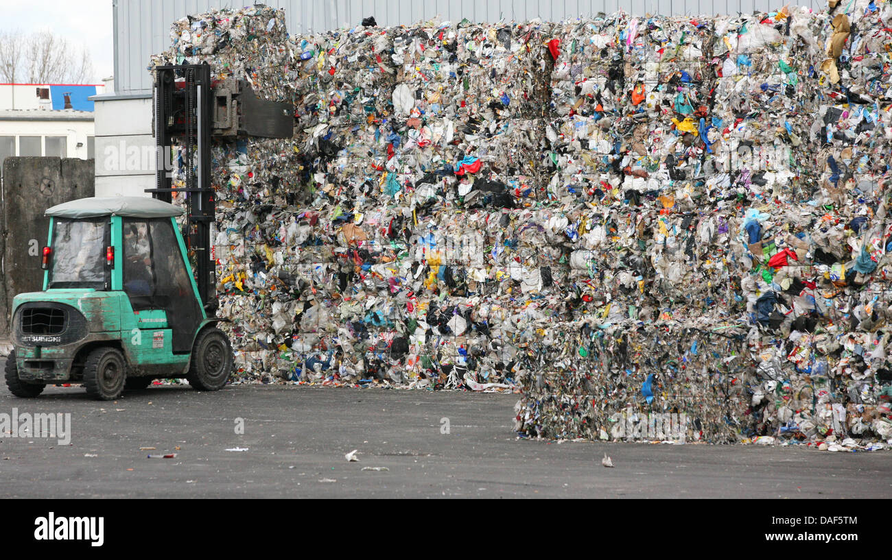 A fork lift processes trash consisting of recyclable plastic at a yard ...