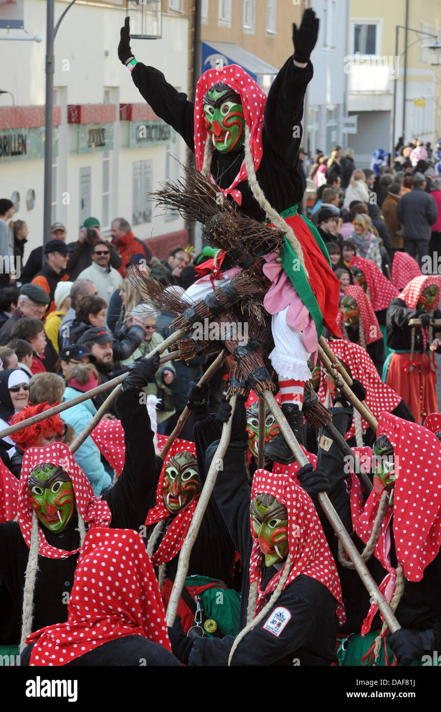 A witch is being carried on brooms by her coven in Sonthofen, Germany ...