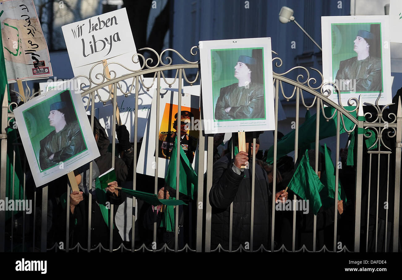 Supporters of the Libyan ruler Muammar Gaddafi wave placards bearing an ...