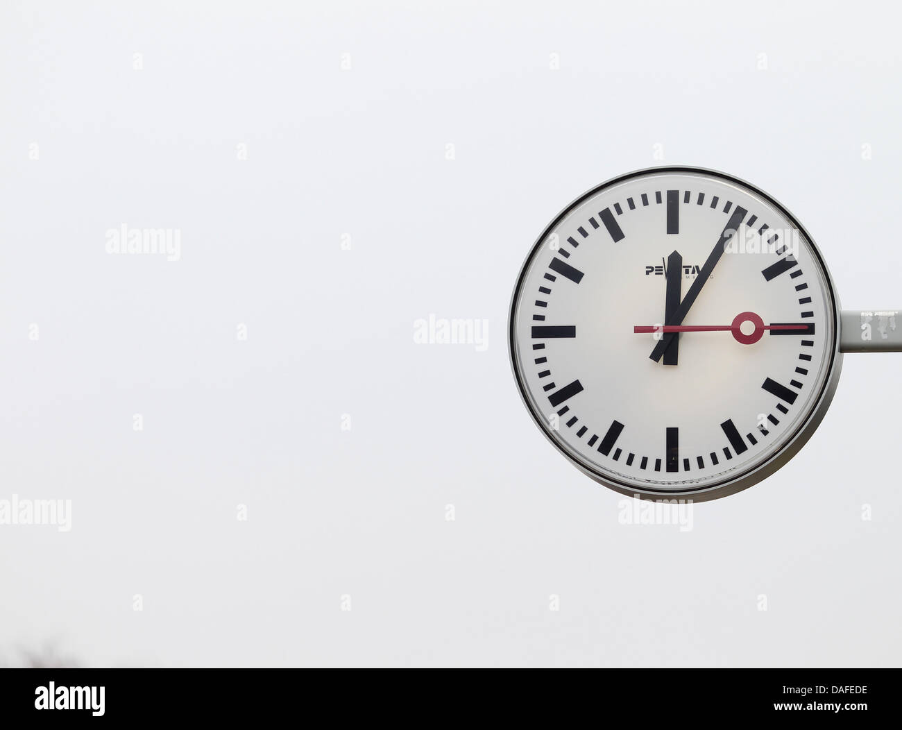 A clock at a railway station shows five past twelve in Thale, Germany ...