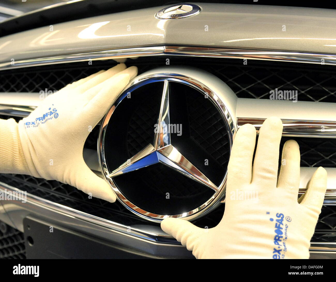 A worker installs a logo on the radiator grille of a Mercedes car in ...