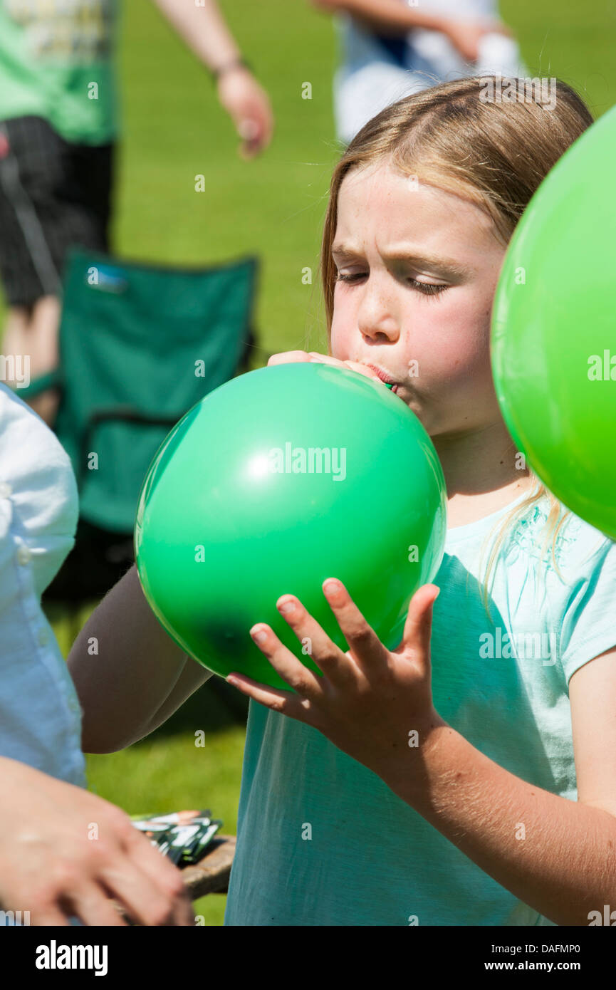Young girl blows up green balloon at Macmillan cancer care charity ...