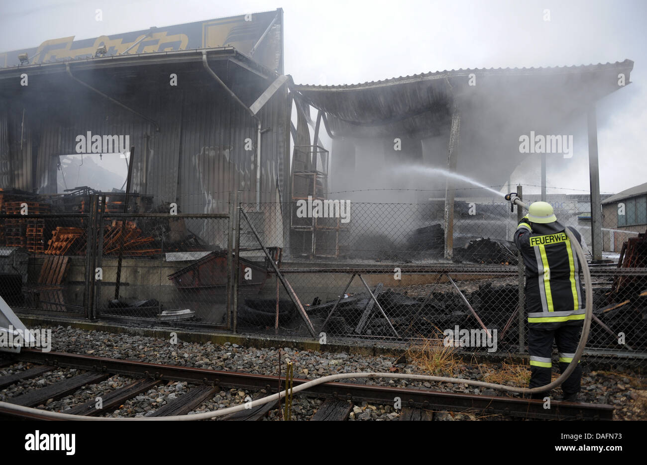 A firefighter extinguishes a fire at a completely burnt out warehouse ...