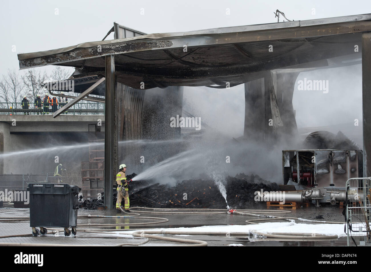 A firefighter extinguishes a fire at a completely burnt out warehouse ...