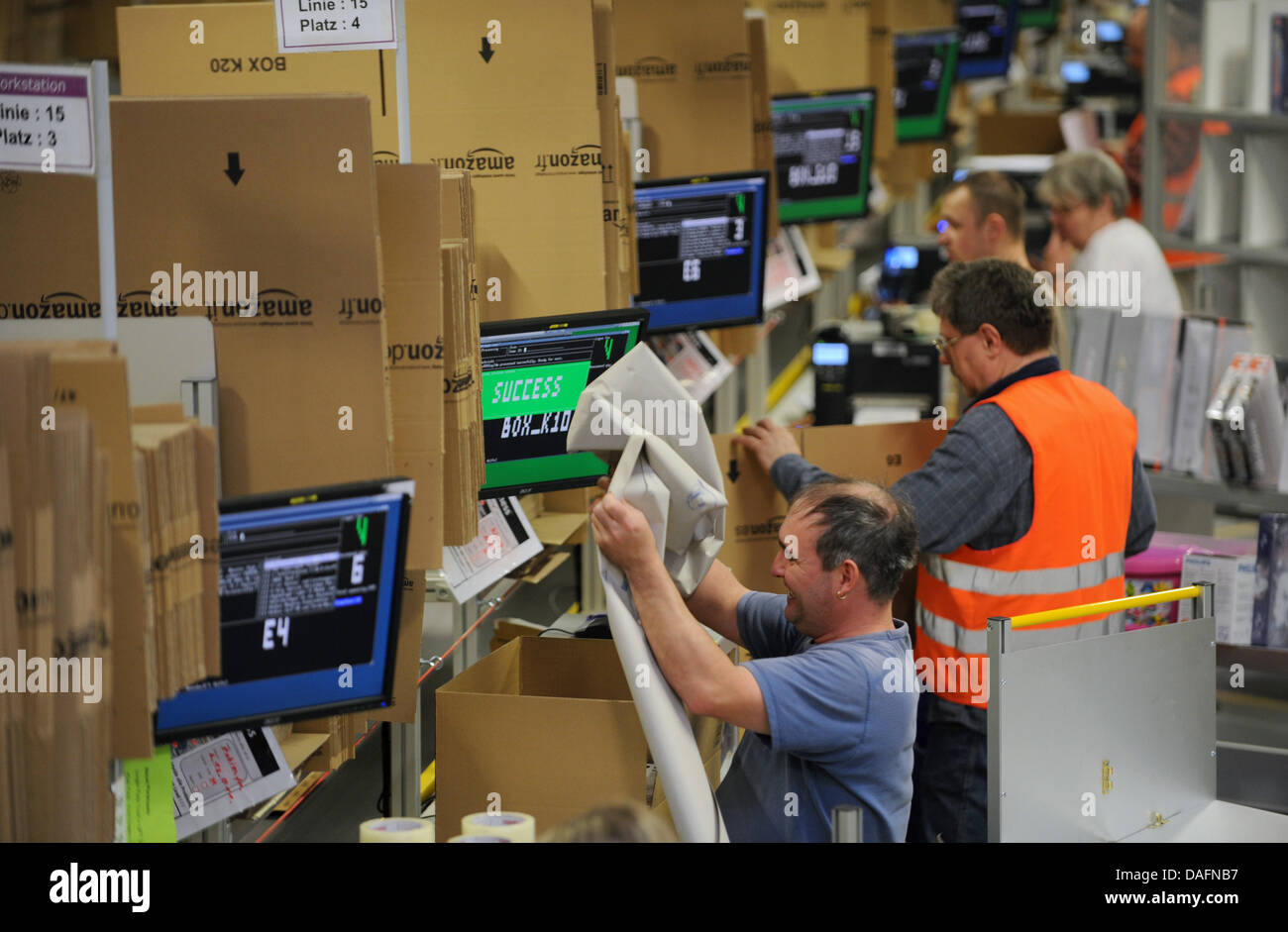 Employees of the online retailer Amazon pack goods at the logistics ...