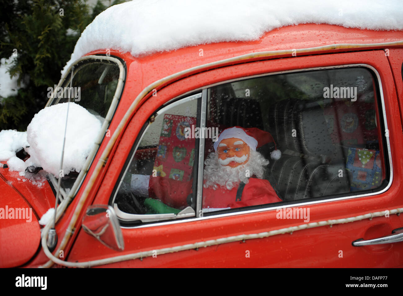A puppet Santa Clause sits behind the steering wheel of a snow-covered ...