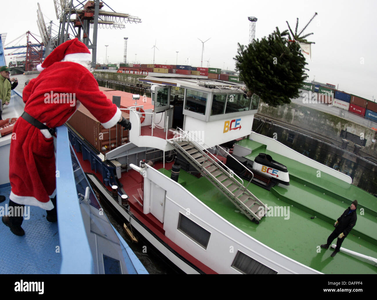 A man dressed as Santa Claus throws a Christmas tree onto a ship at the ...